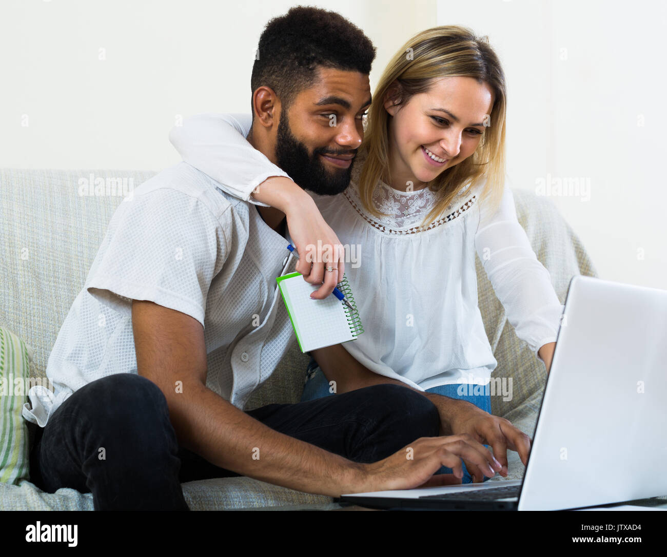 Happy smiling young spouses browsing web and making notes at home Stock ...