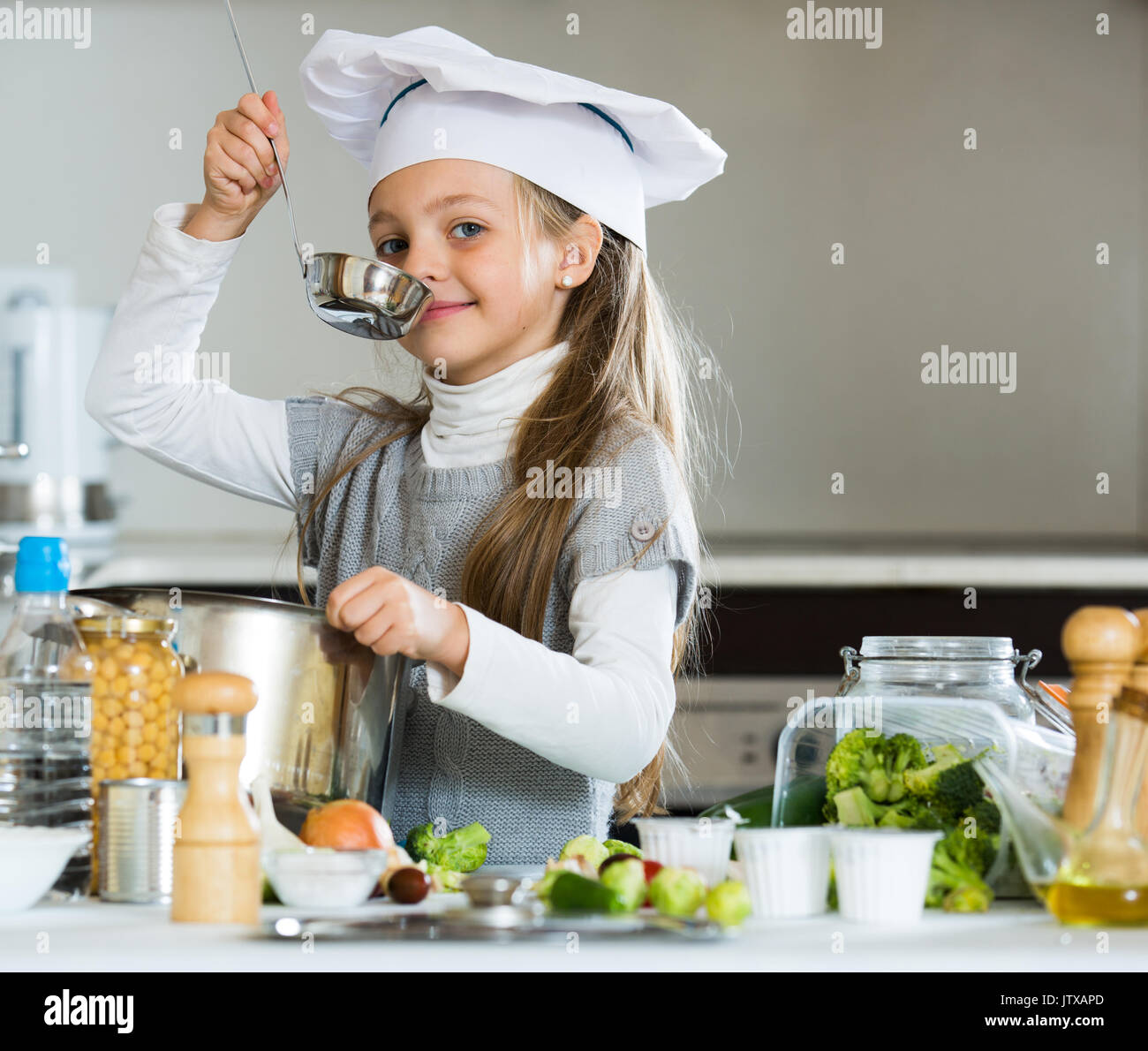 Happy little girl preparing soup for first course at home Stock Photo ...