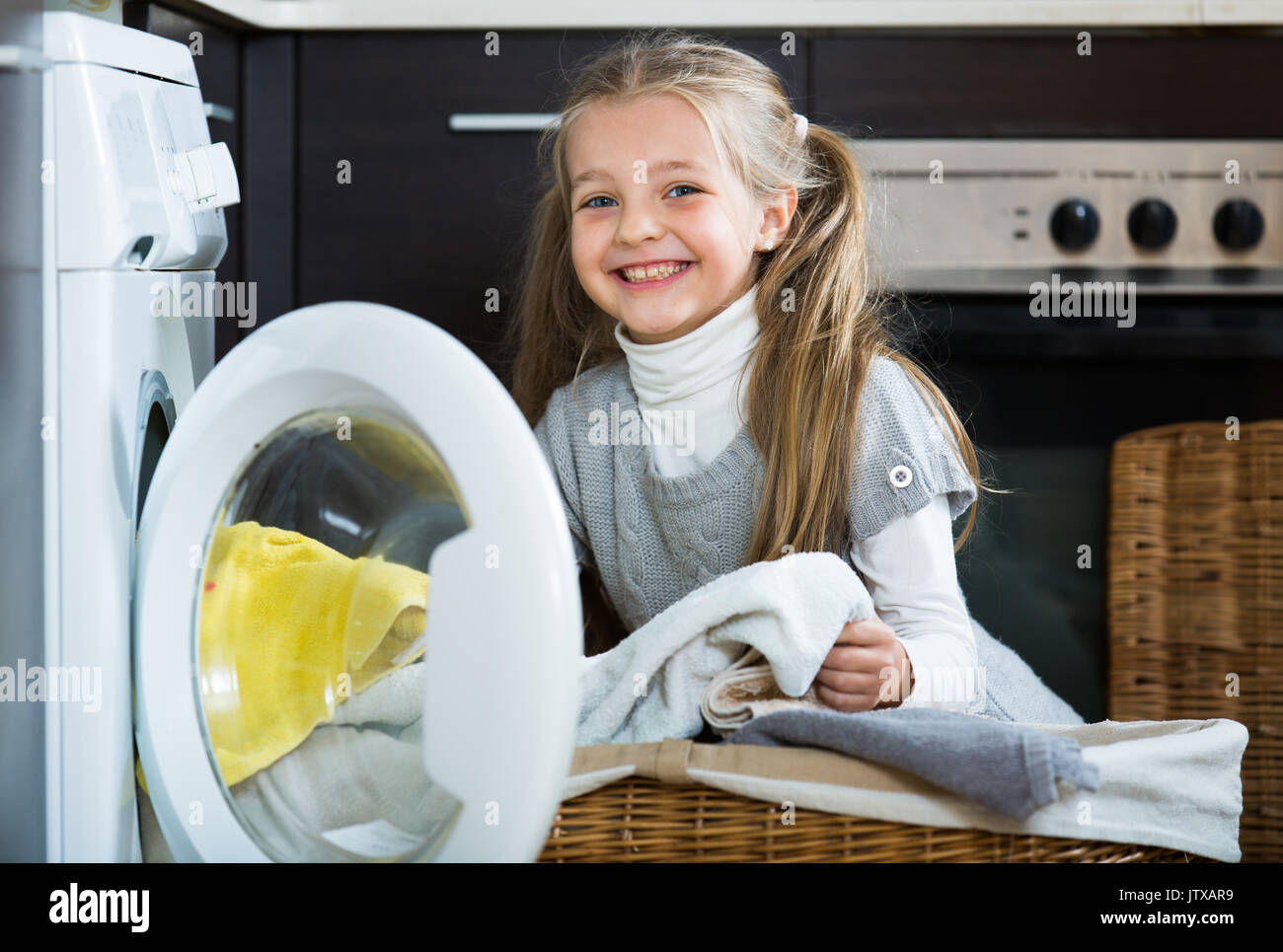 Happy little girl doing laundry in home interior Stock Photo - Alamy