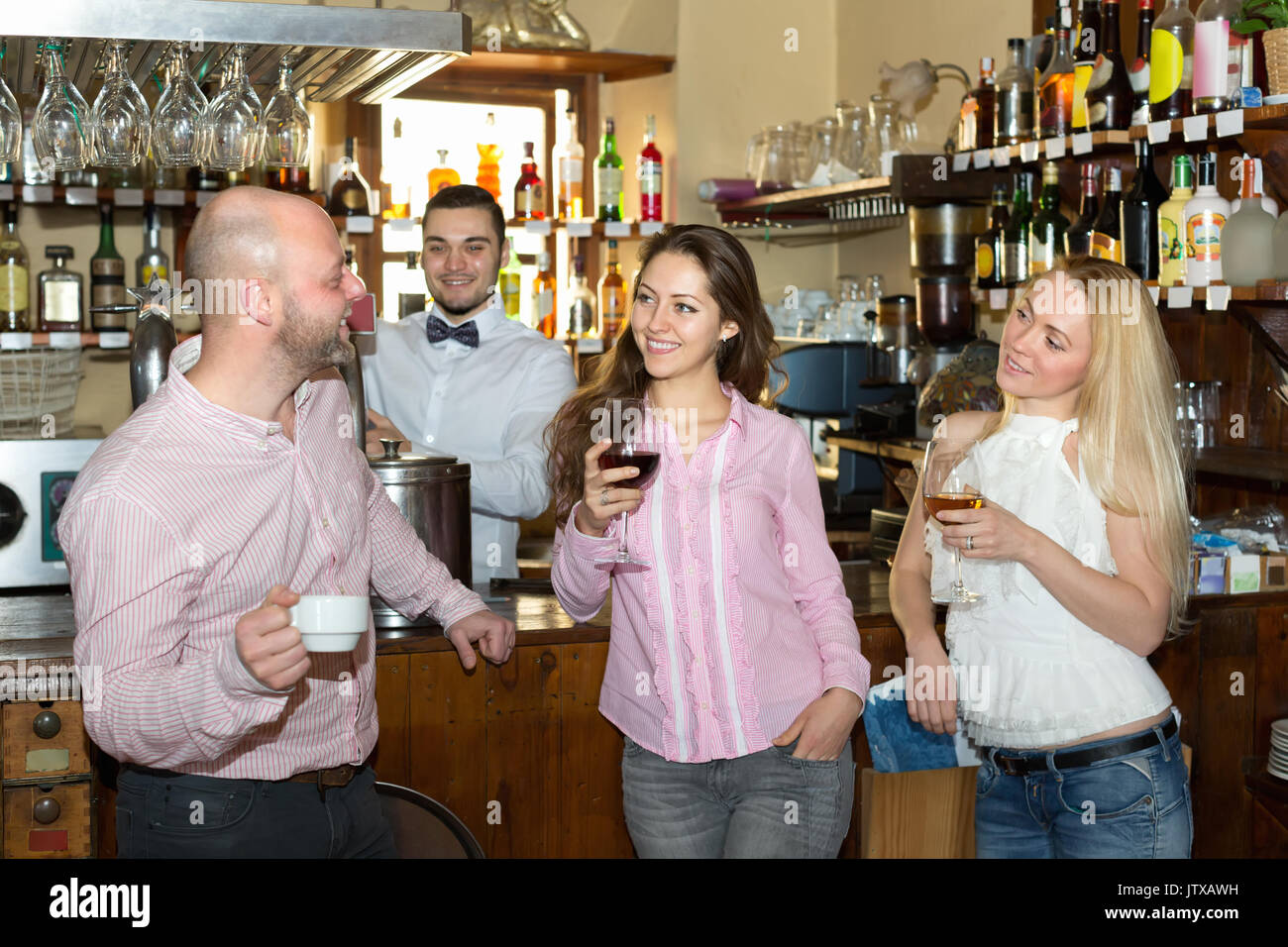 Friends drinking and chatting with friendly barman at bar counter Stock ...