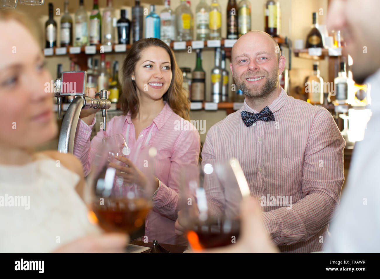 Positive happy bartender entertaining guests at a bar counter Stock ...