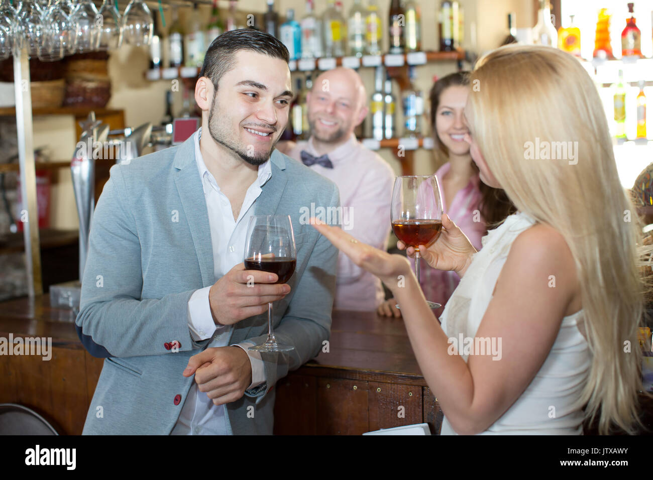 Positive happy bartender entertaining guests at bar counter in bar ...