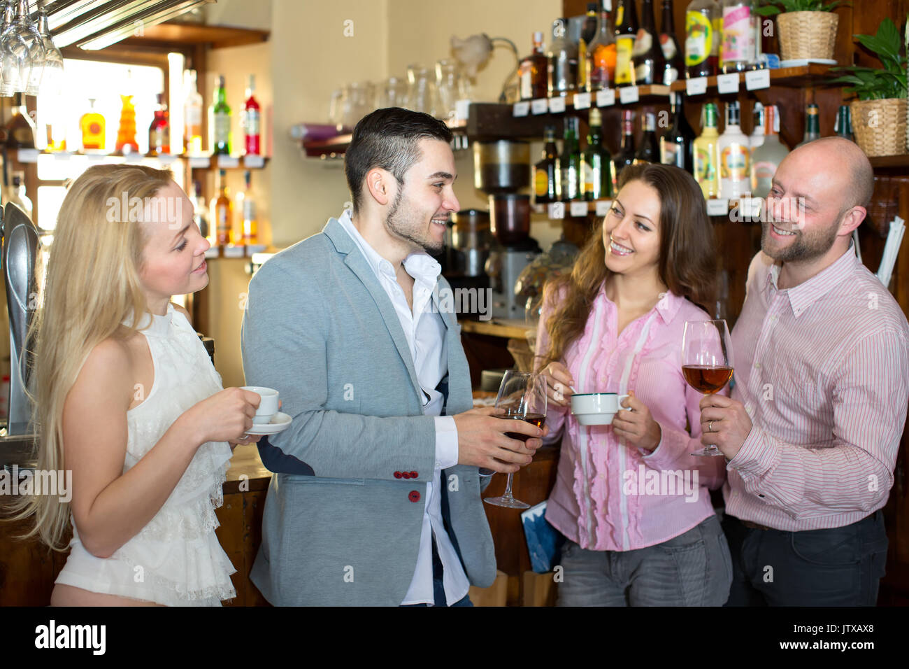 Two beautiful couples having a night out in a bar drinking spirits and ...