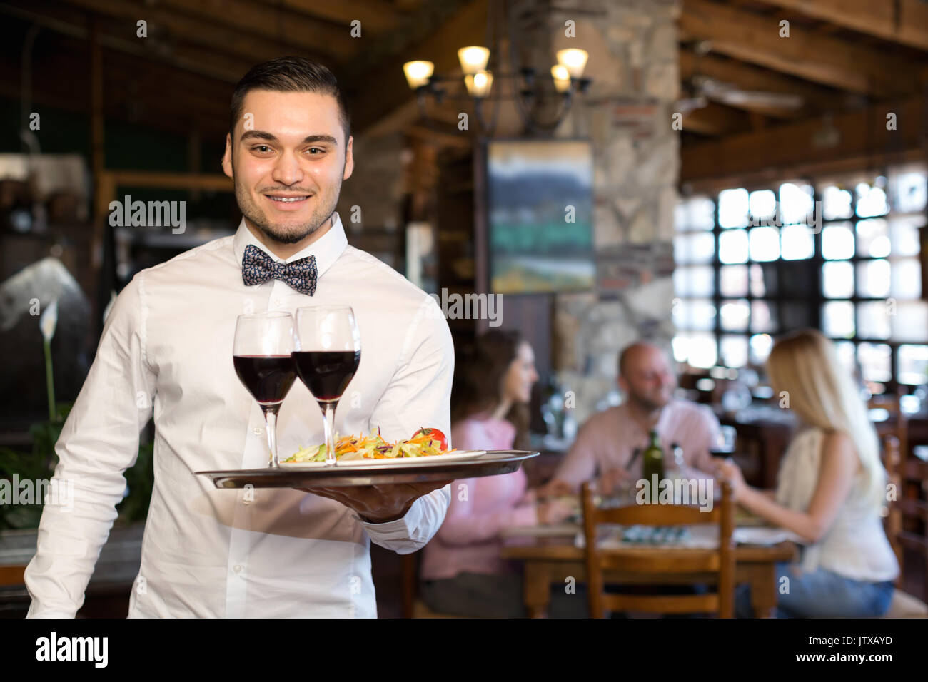 Cheerful adults people having dinner and respectful waiter Stock Photo ...
