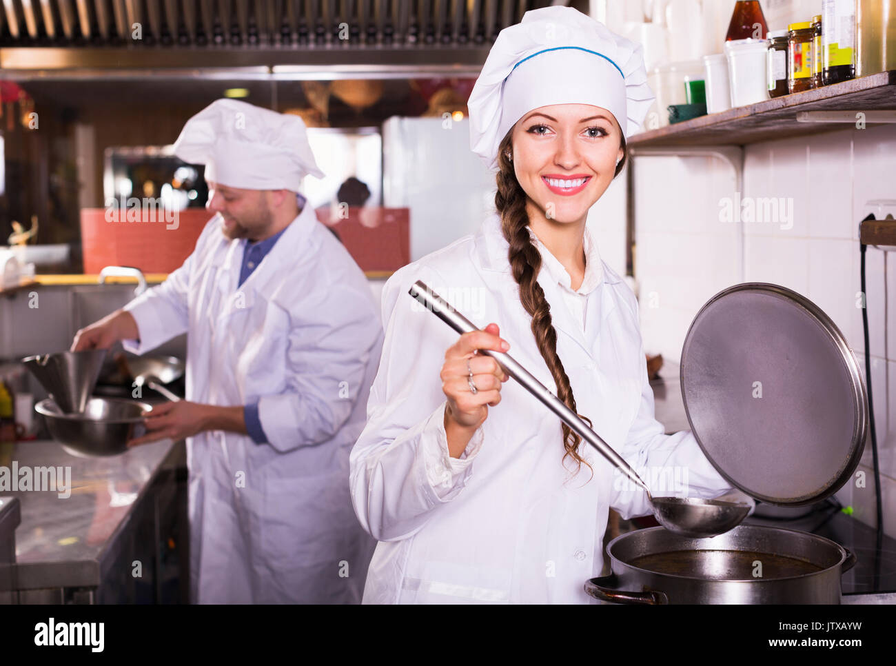 Happy young cooks greeting customers at bistro kitchen and smiling ...