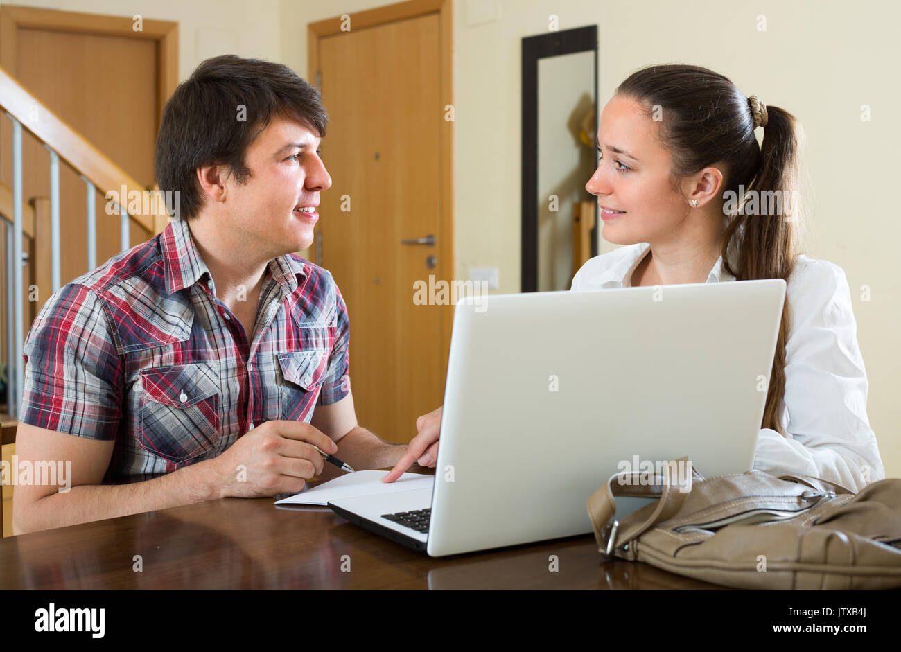 Young couple speaking while working with laptop and papers Stock Photo ...