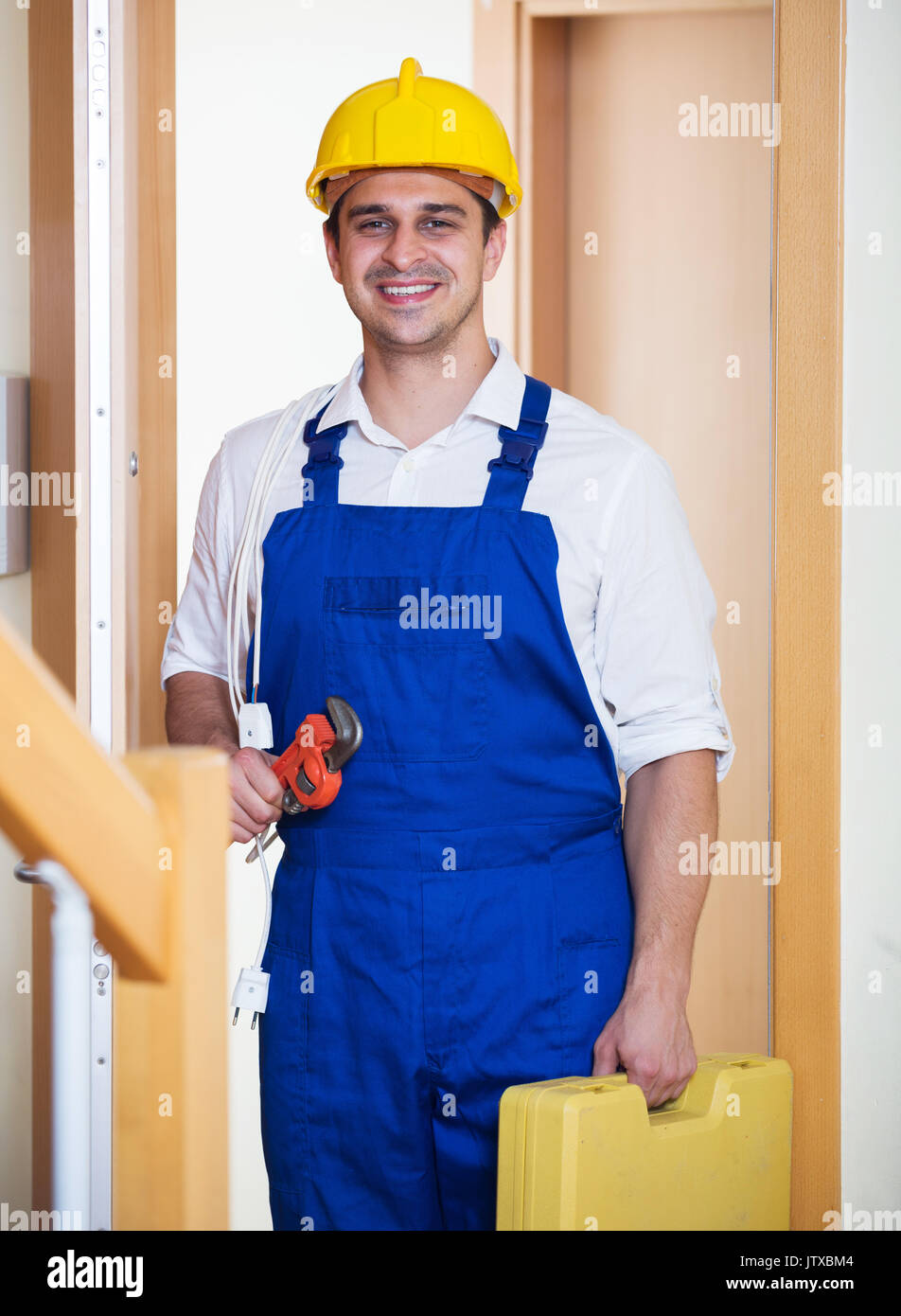 Happy handyman in uniform with tooling at house entrance Stock Photo ...