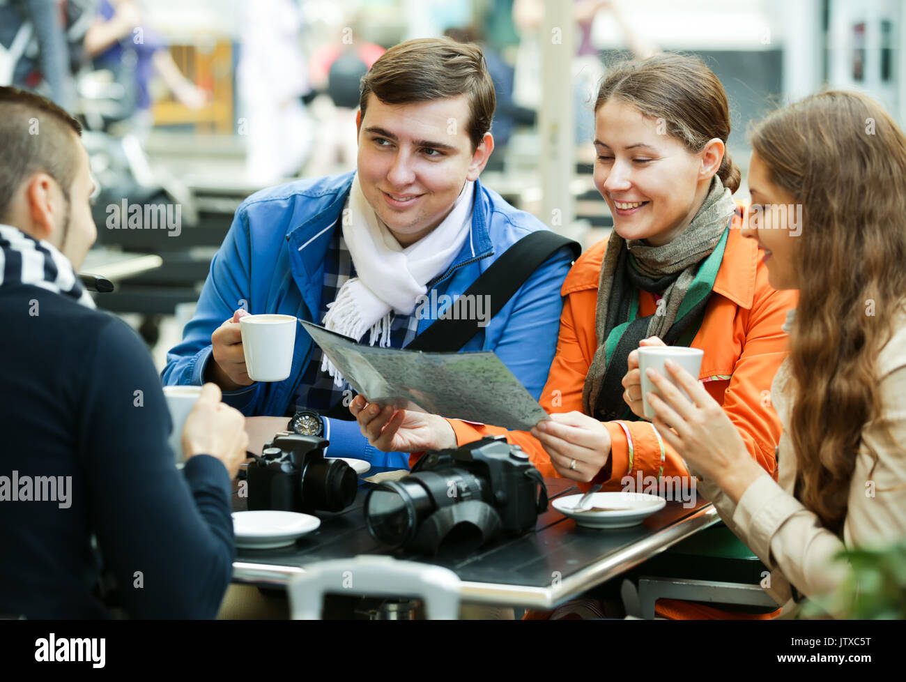 happy tourists drinking coffee at cafe and reading city map Stock Photo ...