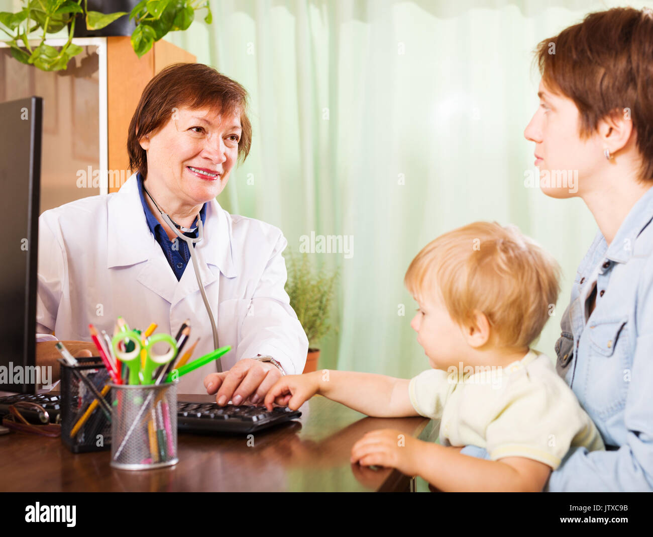 mother with baby talking with friendly pediatrician doctor at clinic ...