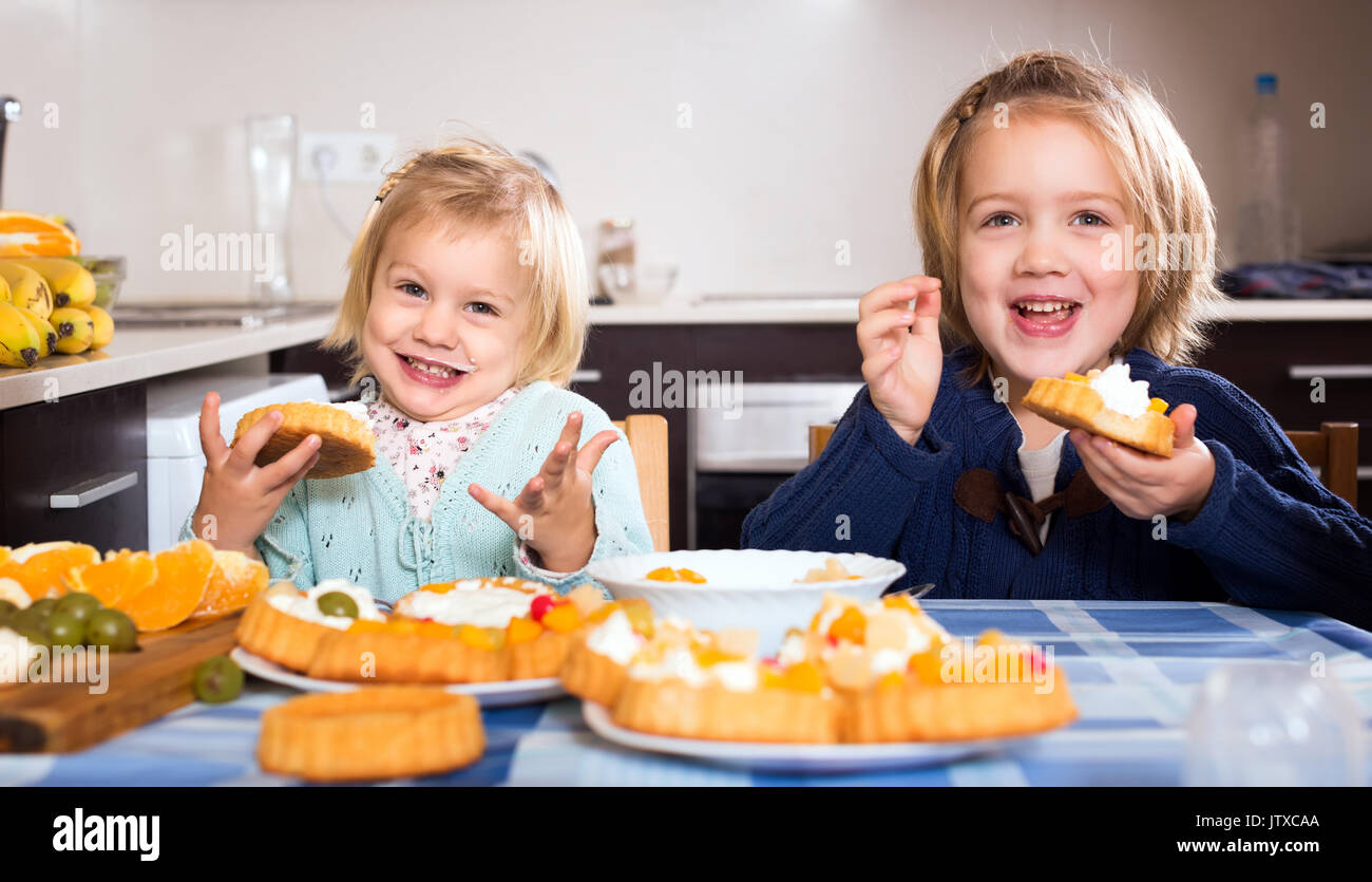 Happy healthy smiling children eating pastry in the kitchen of their ...
