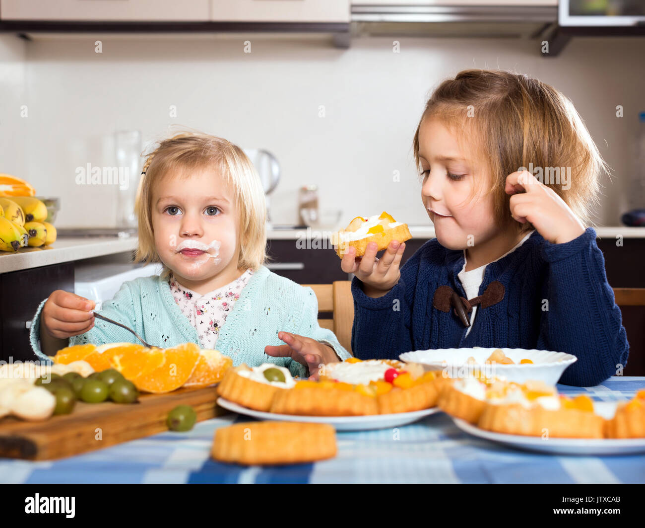 Girls eating delicious pastry dessert in the kitchen with their faces ...