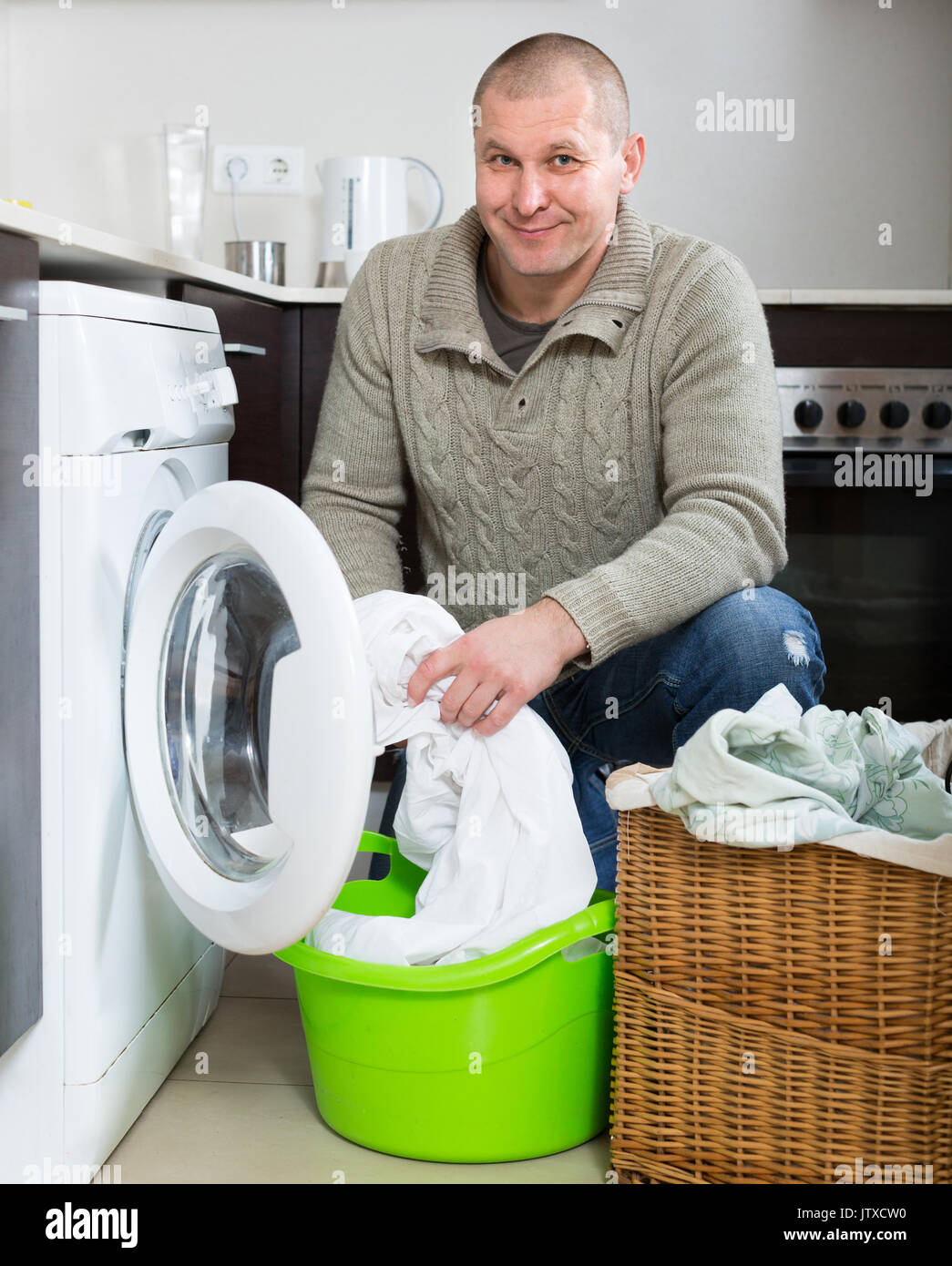 Home laundry. Ordinary smiling man using washing machine at home Stock ...