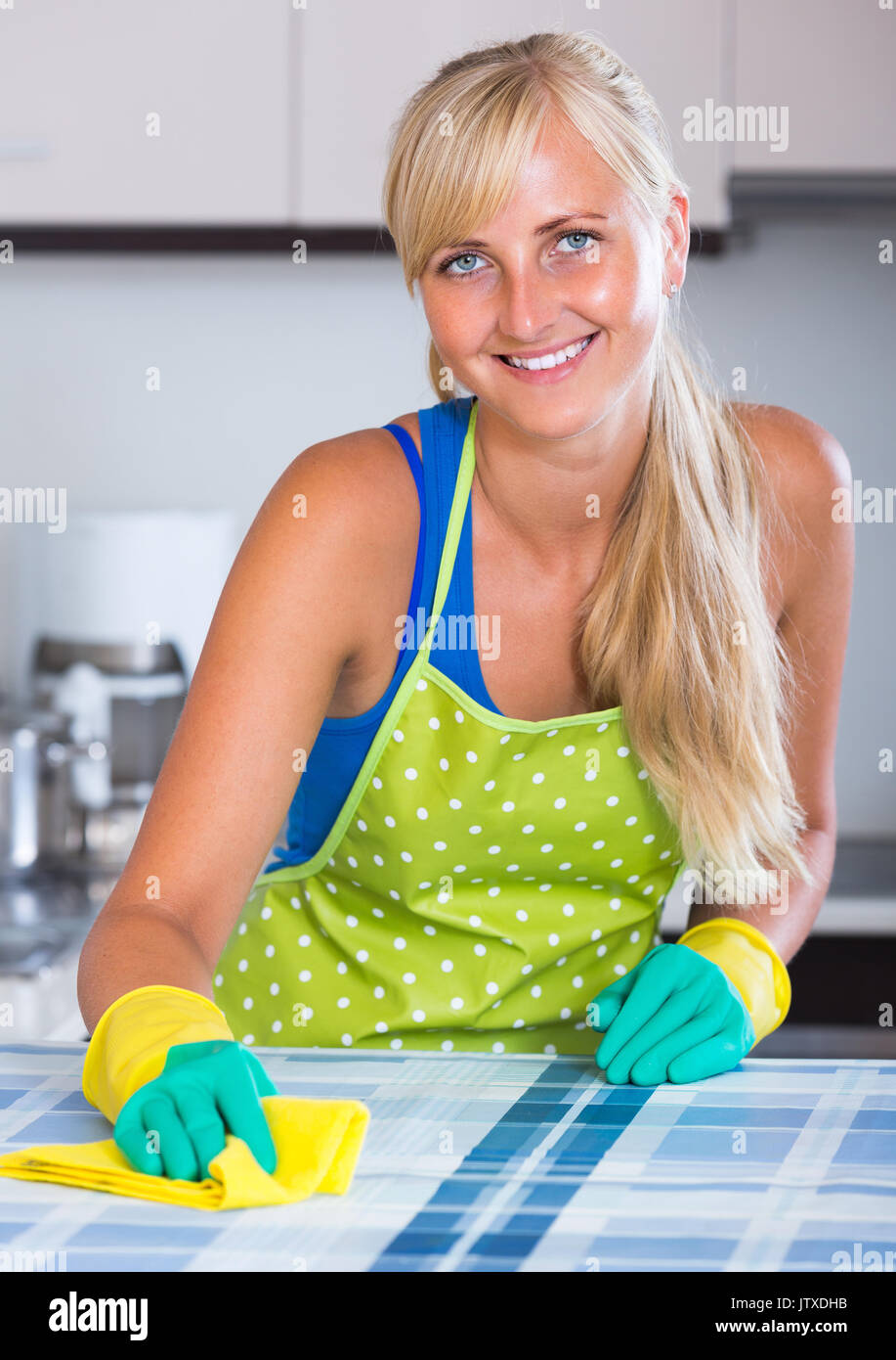 Smiling young blonde maid dusting kitchen tops Stock Photo - Alamy