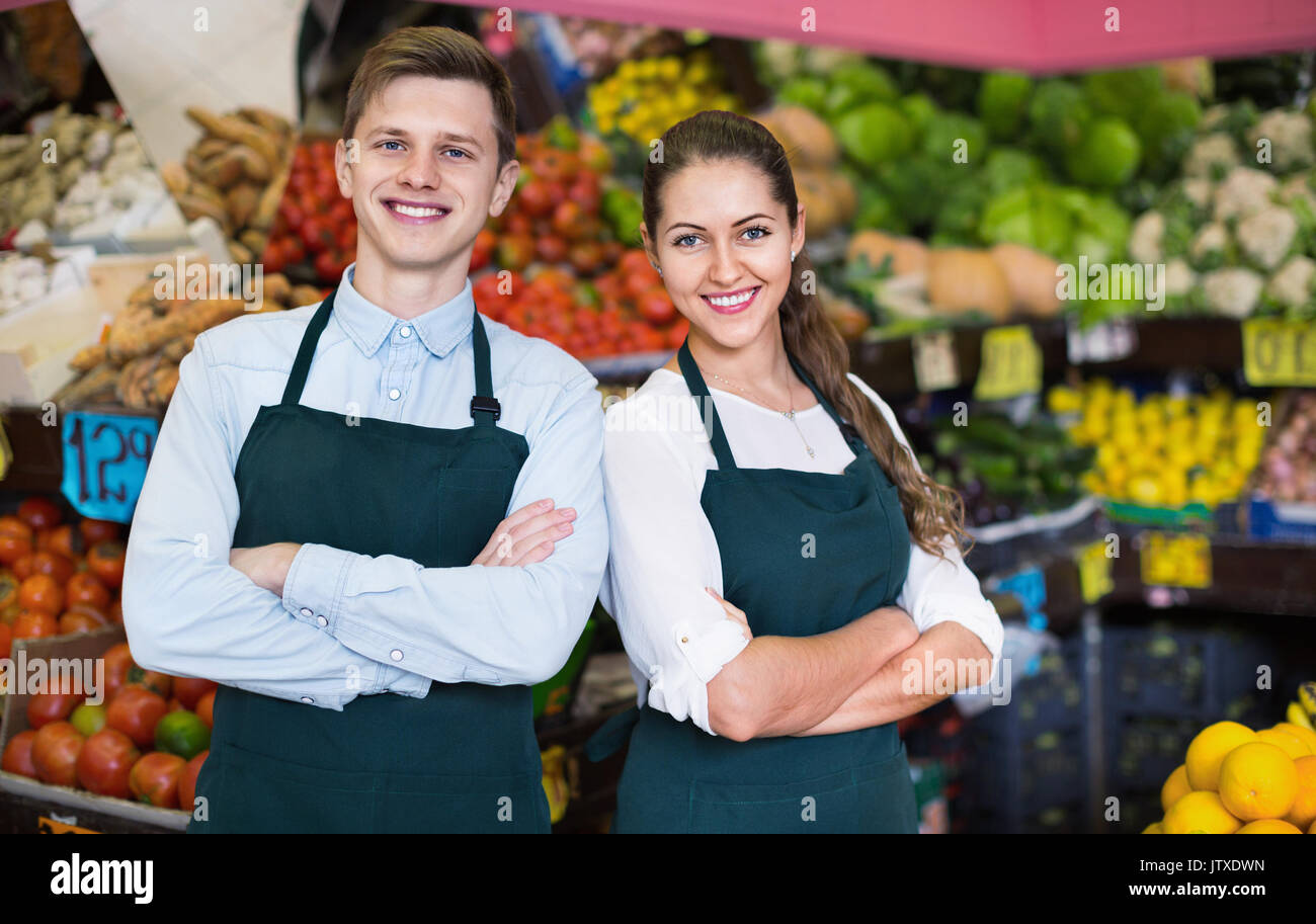 Friendly sellers having vegetables and fruits on displays of market ...