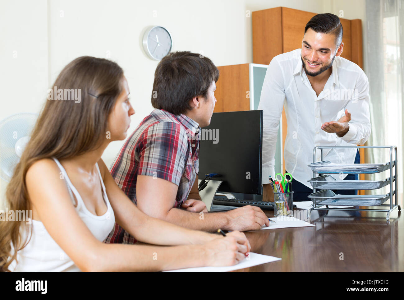 Salesman with young couple signing business contract in the office ...