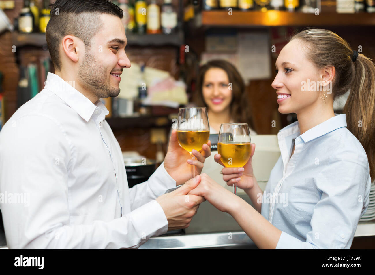 Young smiling restaurant visitors waiting for table and drinking wine ...