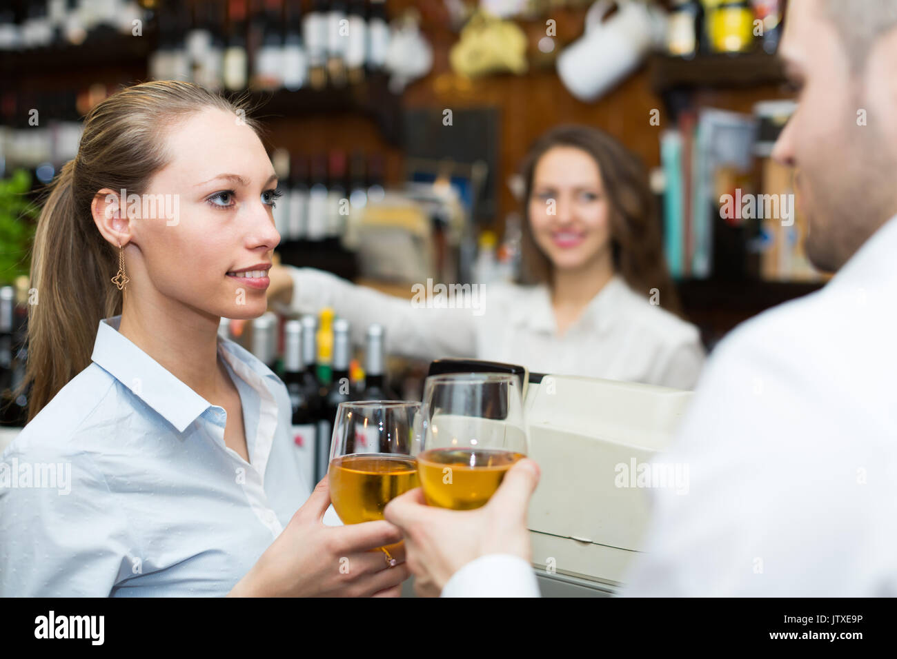 Happy bartender and guests couple with wine at bar counter. Focus on ...