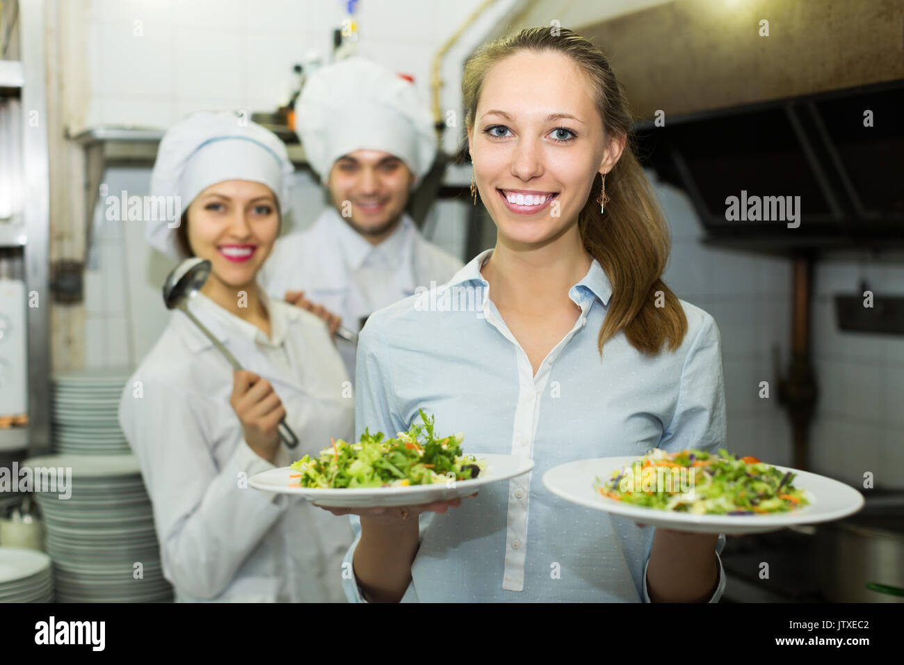 Cook gives to smiling female waitress plates with prepared meal at ...