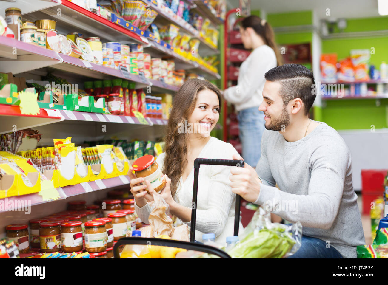 Positive people standing near shelves with canned goods at shop Stock ...