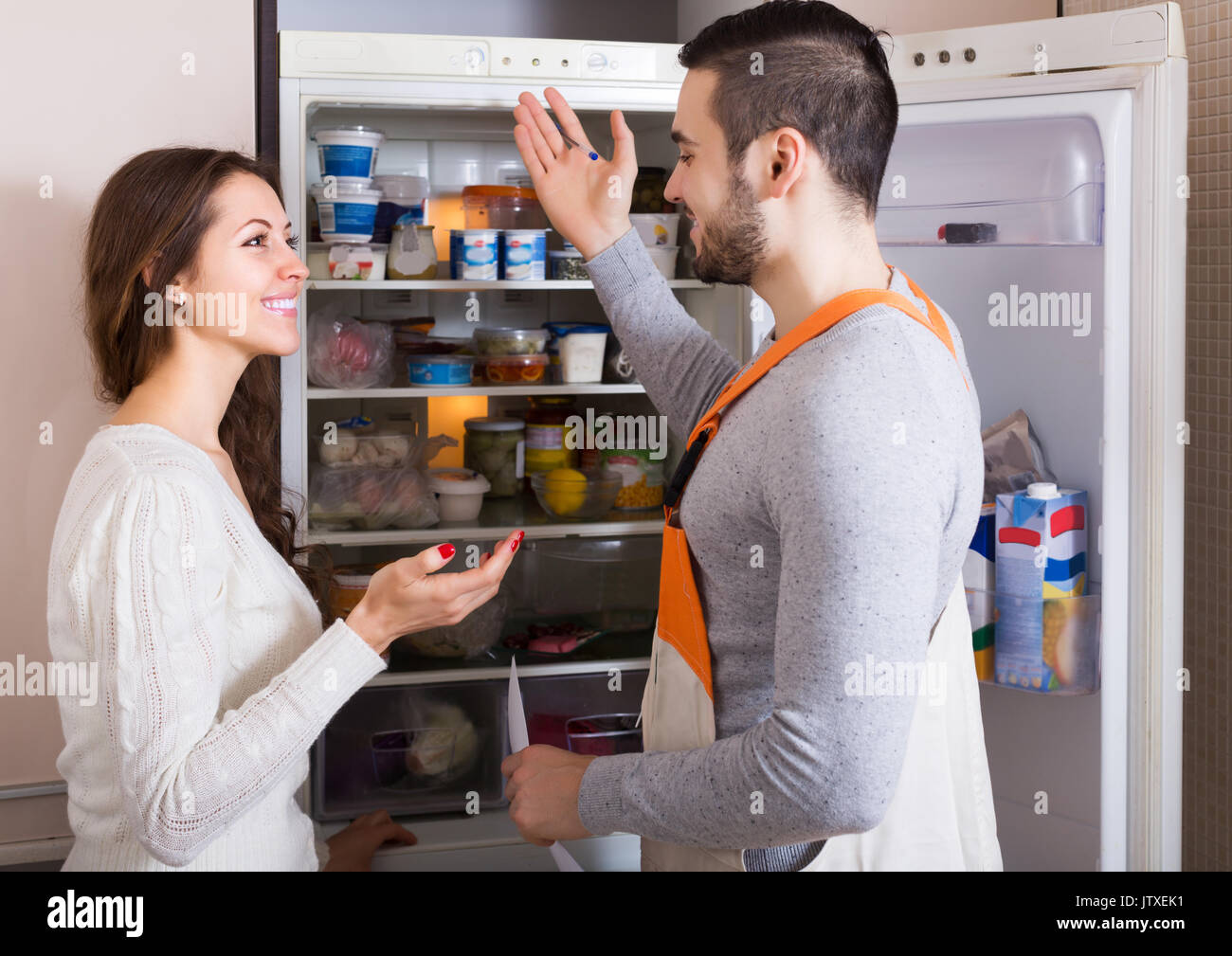 Young woman showing broken refrigerator to smiling repairman Stock ...
