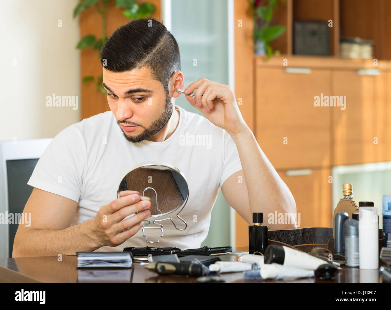 Handsome man remove hair from his ear with pincers Stock Photo - Alamy