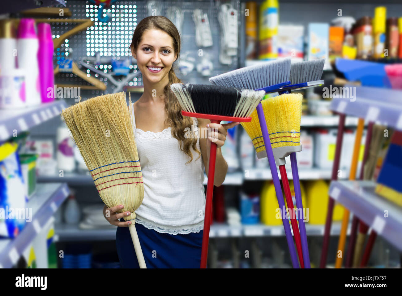 Young smiling housewife chooses broom for cleaning Stock Photo - Alamy