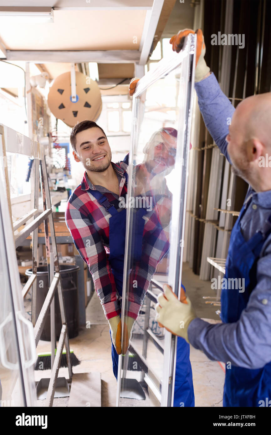 Two workers in uniform inspecting windows at workshop Stock Photo - Alamy