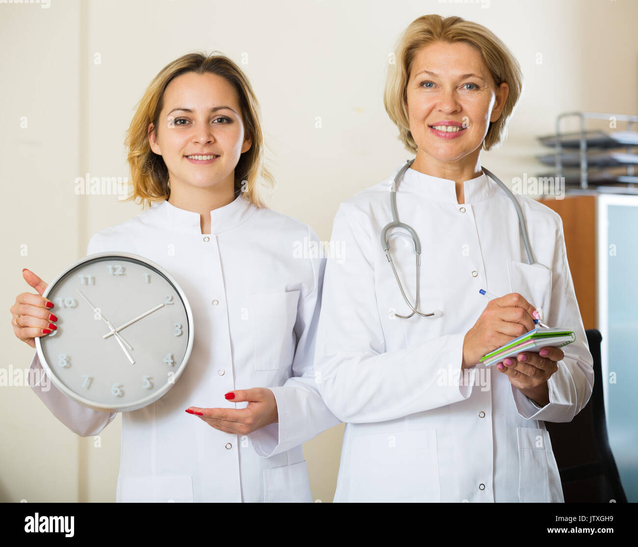 Two professional doctors with stethoscope and big clock in office Stock ...