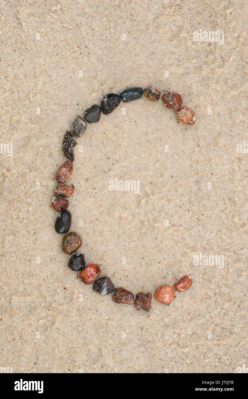 pebble c letter on sand background Stock Photo - Alamy