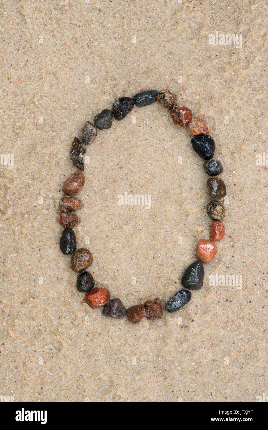 pebble o letter on sand background Stock Photo - Alamy