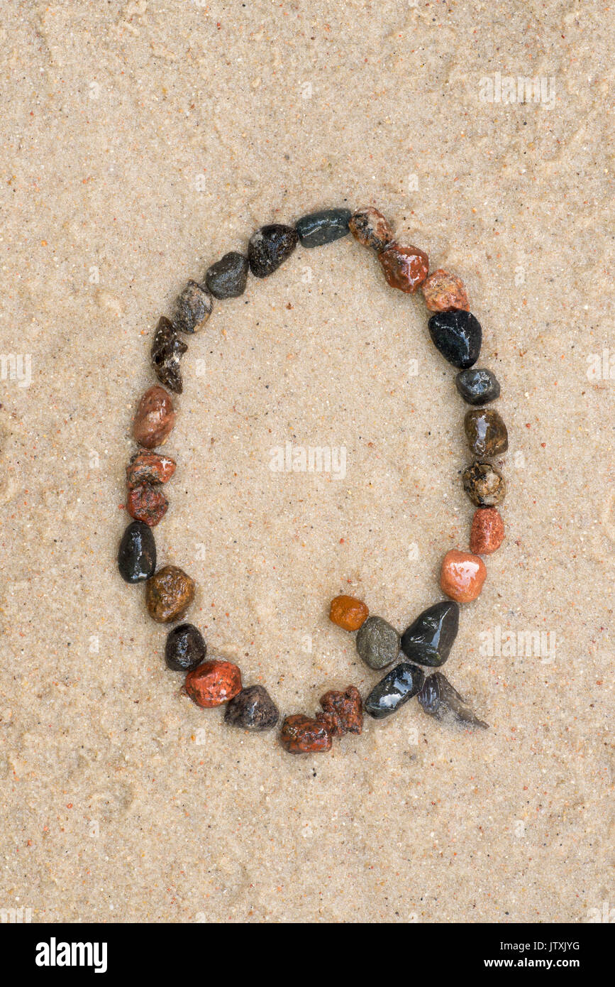 pebble q letter on sand background Stock Photo - Alamy