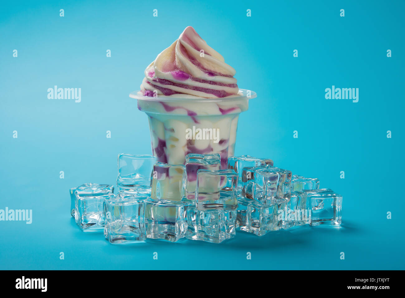 side view cup of strawberry flavor ice cream and ice cube on blue ...
