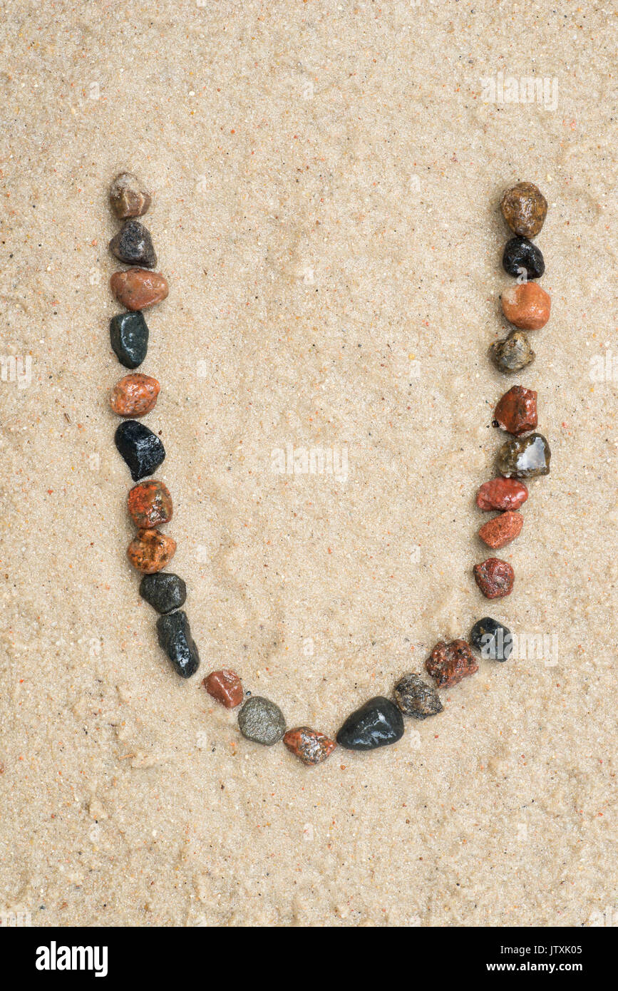 pebble u letter on sand background Stock Photo - Alamy