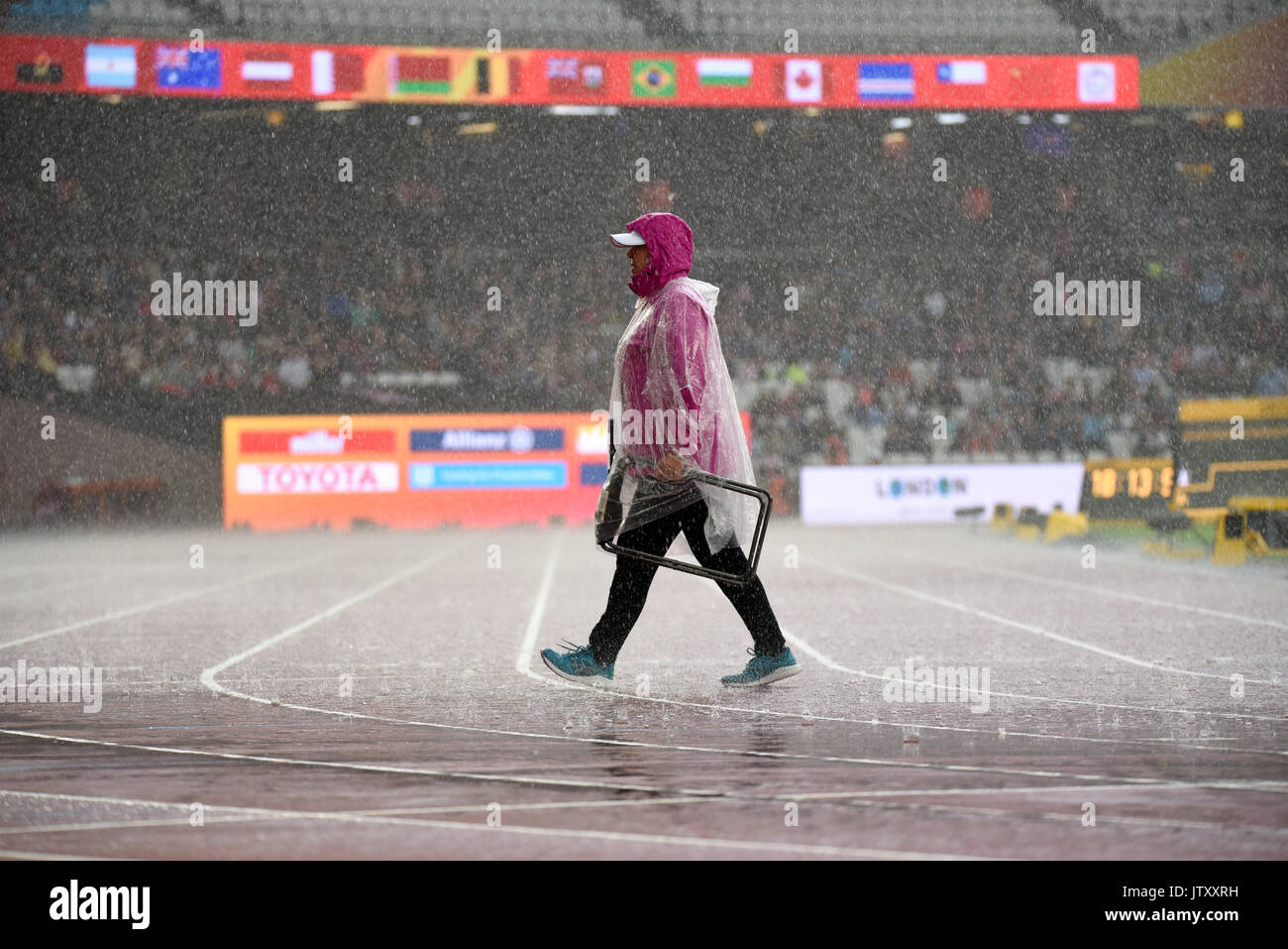 An official walking across the running track in pouring rain at the ...