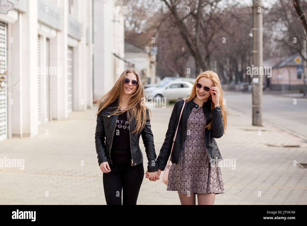 Two girl friends hanging out outside in the city Stock Photo - Alamy