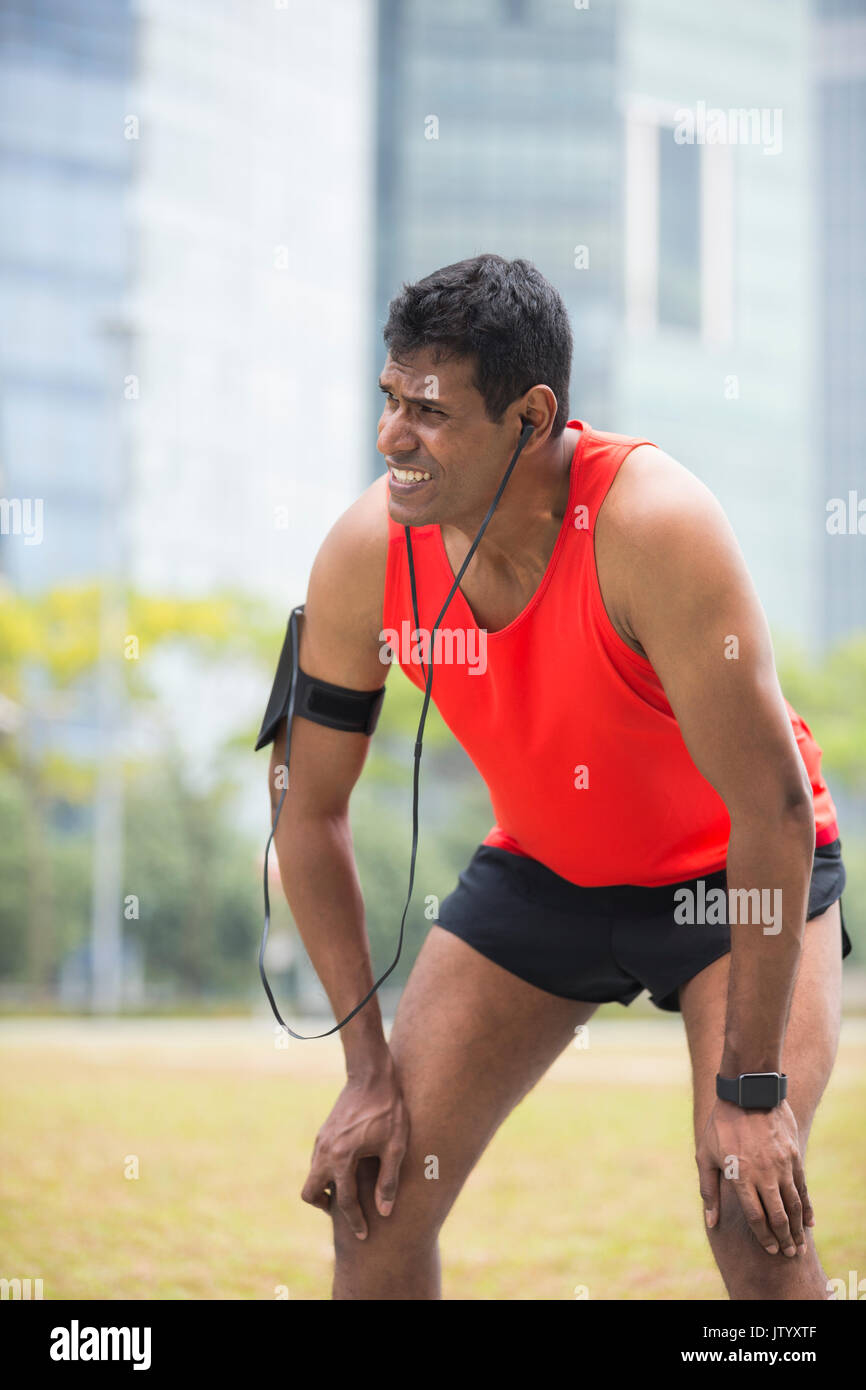 Portrait of athletic Indian man resting after urban run through city ...