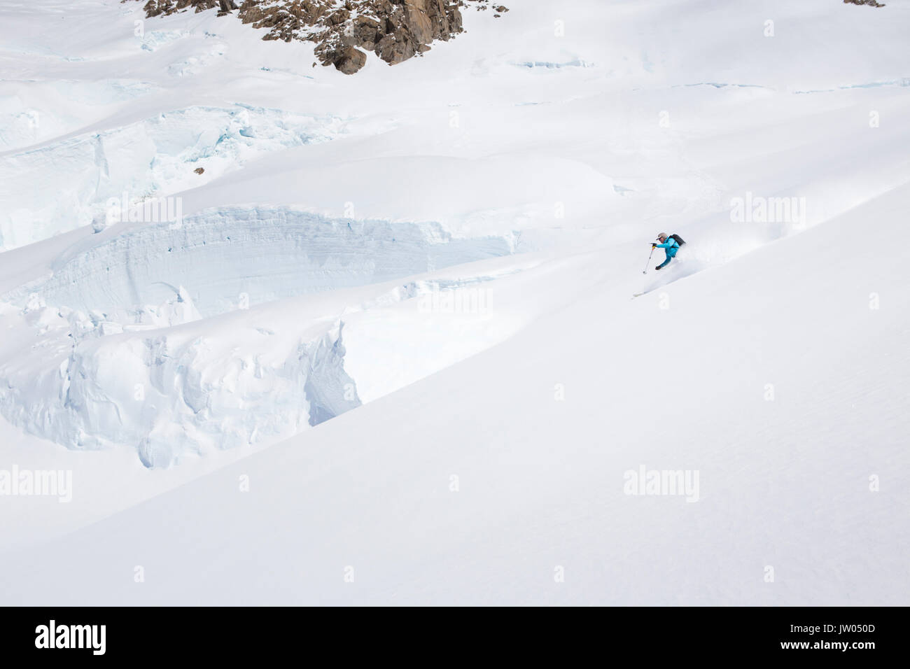 A mountaineers is skiing down a glacier slope at 14.000 feet on Denali ...