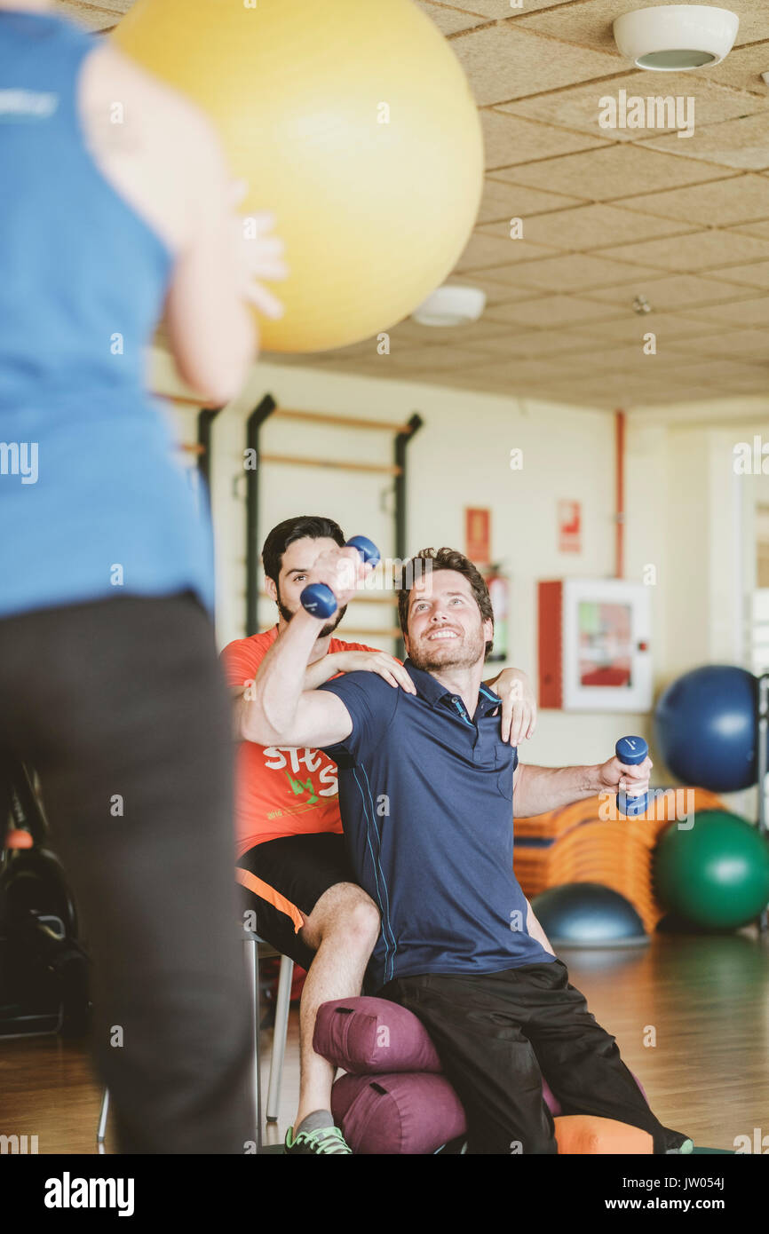 Young man practicing with dumbbells during physiotherapy session Stock ...
