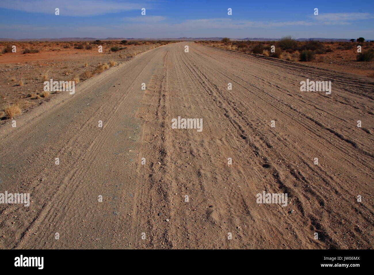 Landscape with wide dusty open dirt road leading to a faraway blue ...