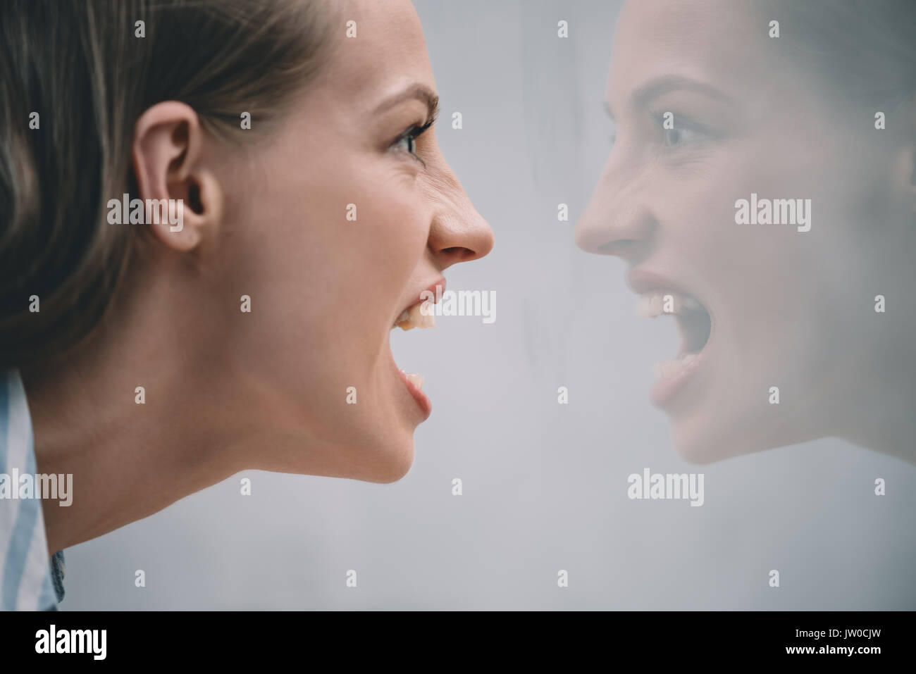 aggressive stressed woman screaming at her reflection in mirror Stock ...