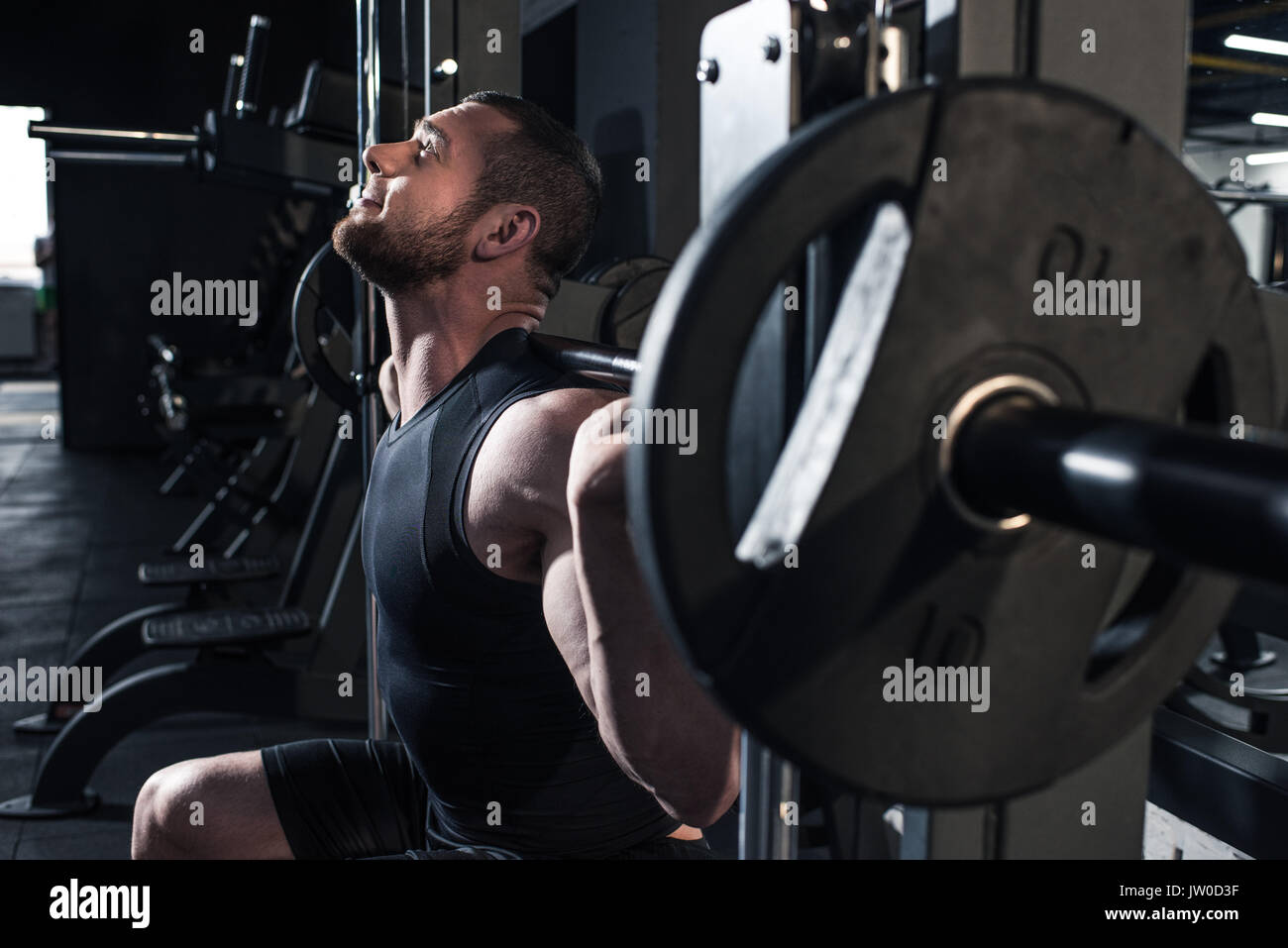 side view of sportive man lifting barbell at gym Stock Photo - Alamy