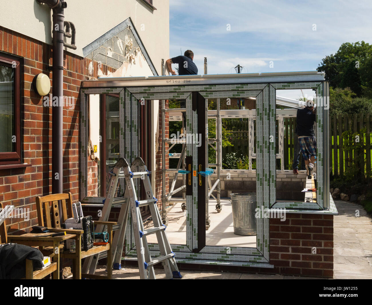 Three workmen installing the metal frame of a new conservatory UK Stock ...