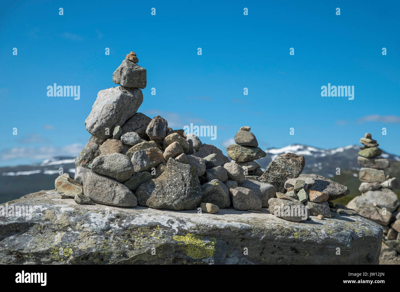 balanced stack of stones at Eidfjorden, Norway with snow and mountains ...