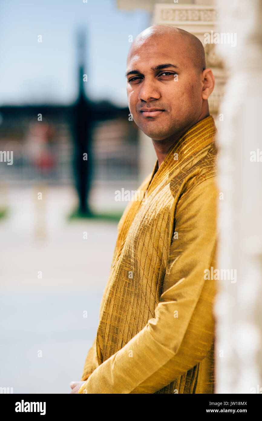 The handsome Indian man wears a gold kurta and posed at a temple Stock ...