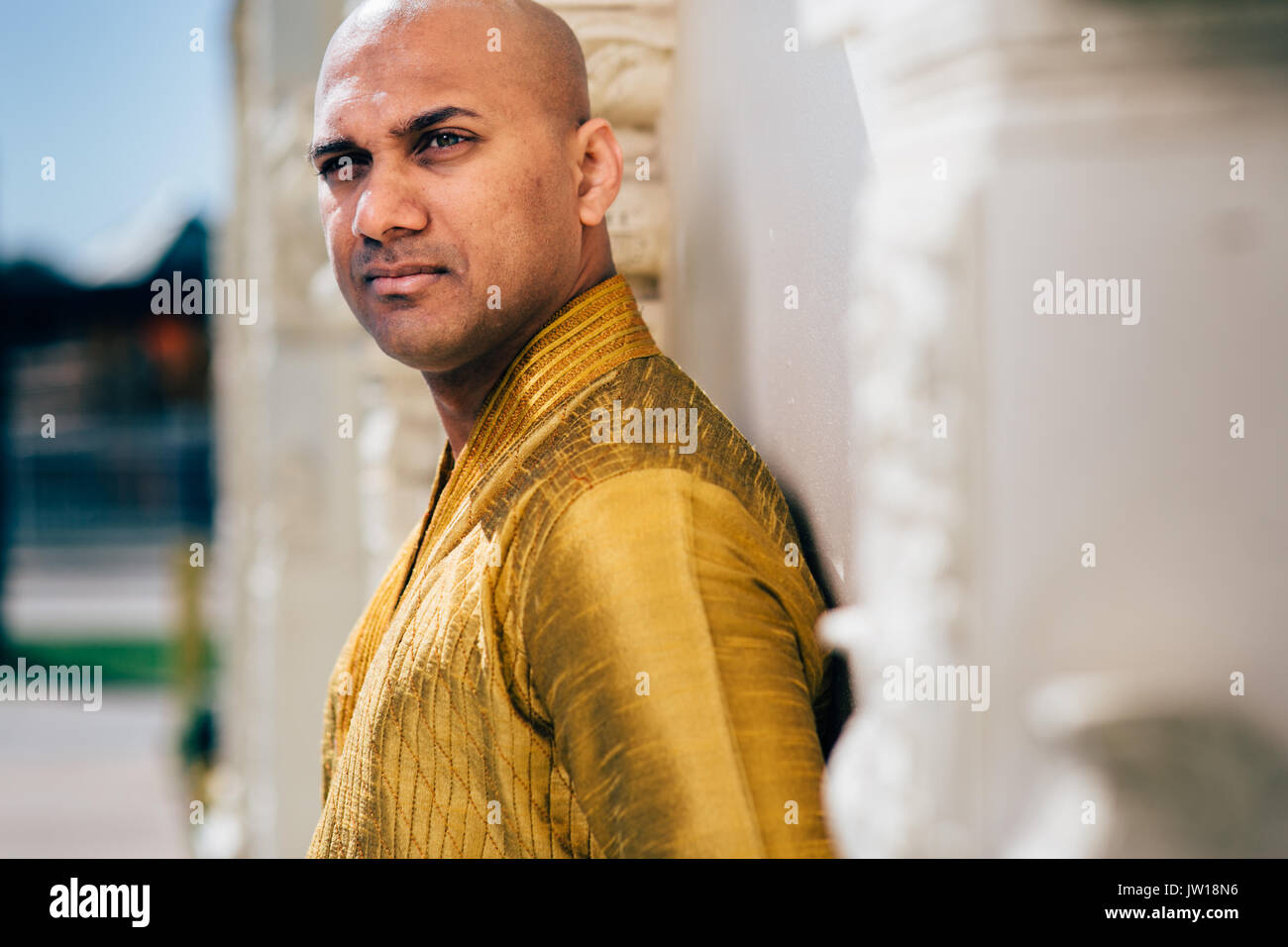 The handsome Indian man wears a gold kurta and posed at a temple Stock ...