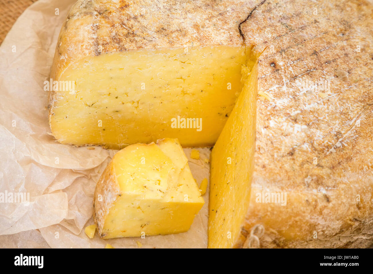 Cheese heads with a slice cut off on wooden table Stock Photo - Alamy