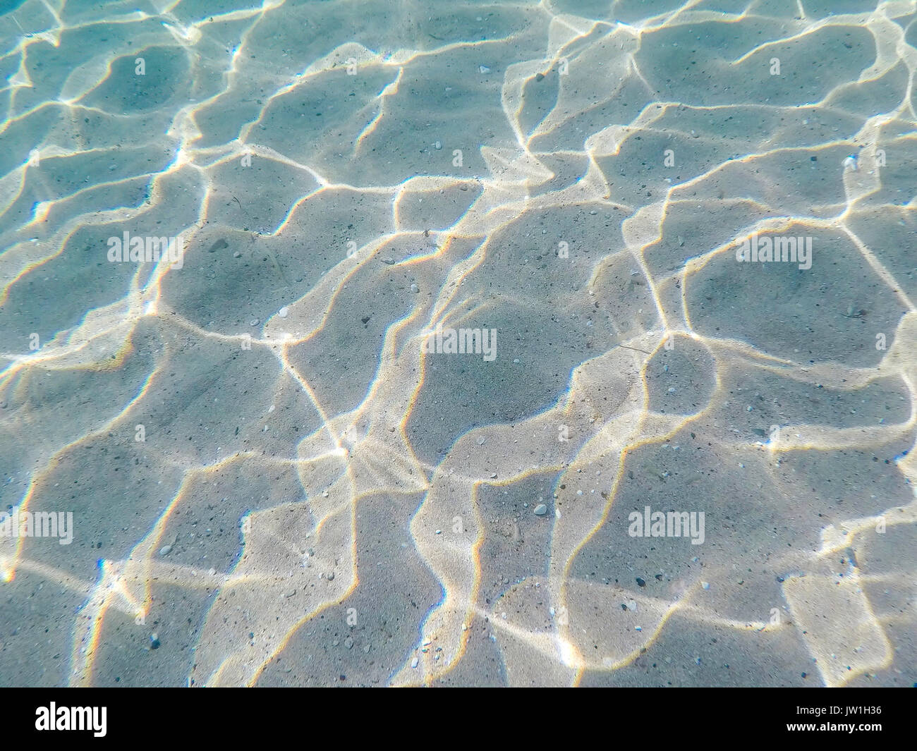 Sunlight reflecting on a the bottom of a shallow underwater bay. Sandy ...