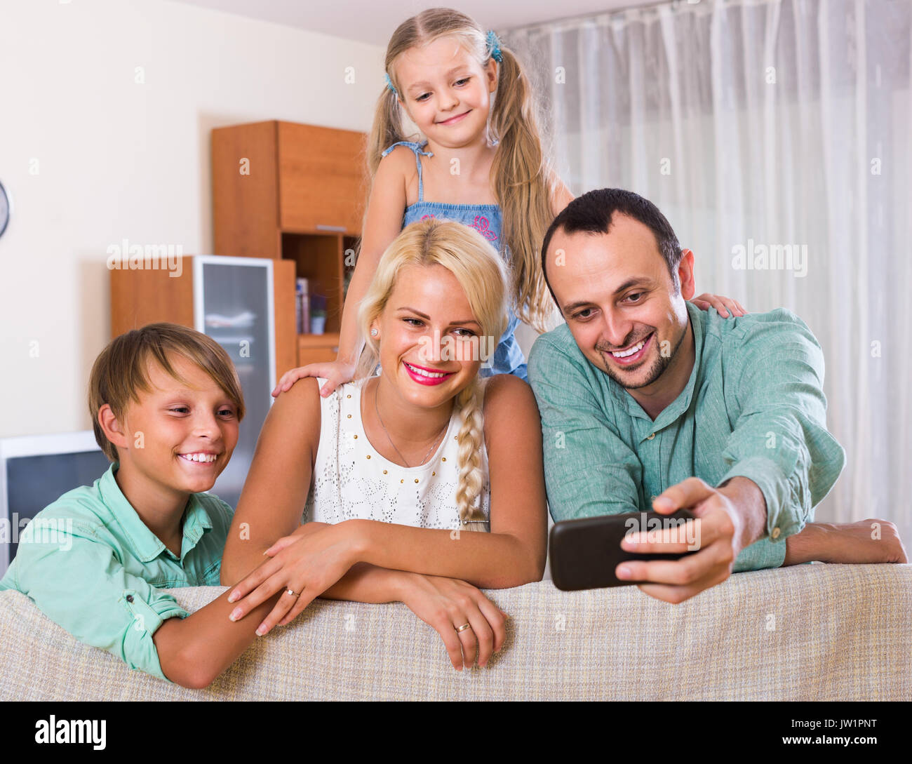 happy spanish parents with two children posing in home interior Stock ...