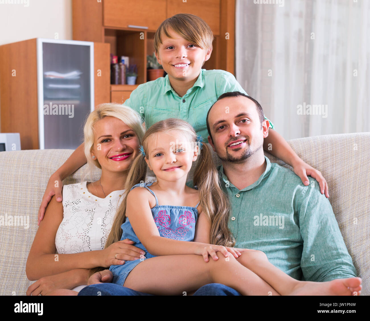happy parents with two children posing in home interior Stock Photo - Alamy