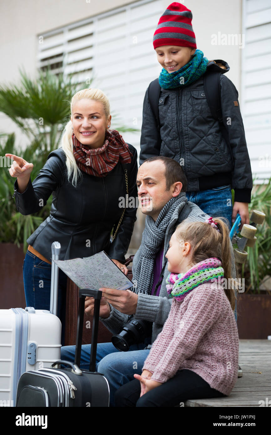Happy middle class family of four checking direction in a map outdoor ...